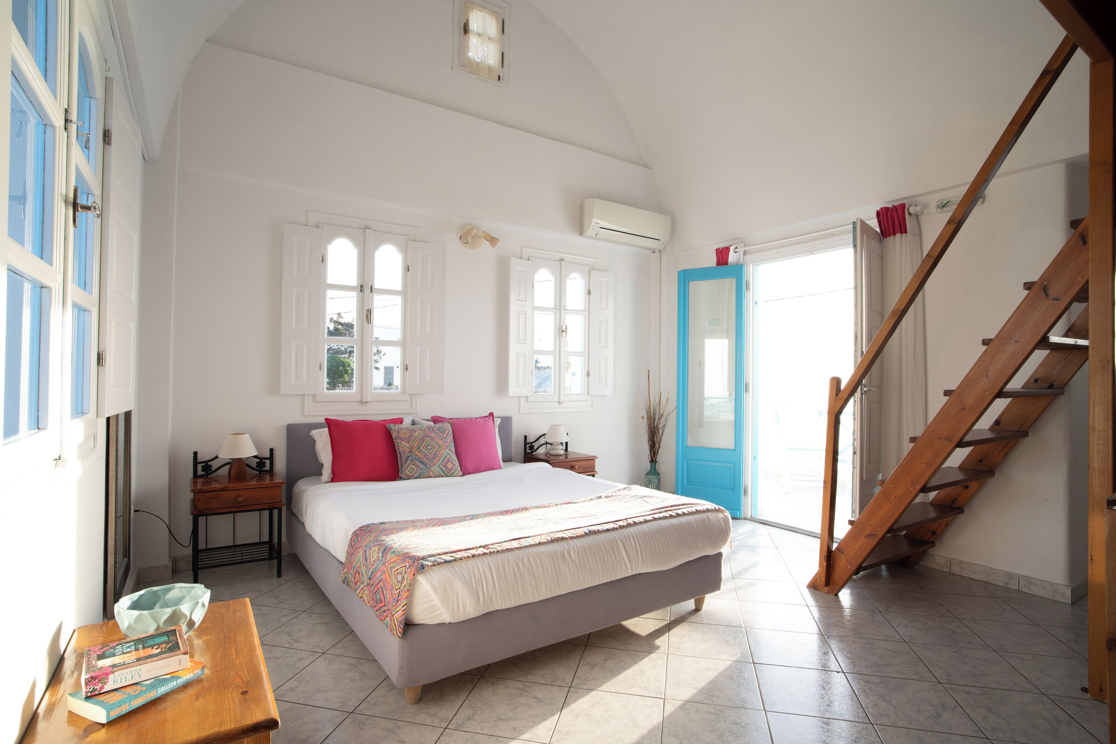 Quarto espaçoso com uma cama grande, escada de madeira e vista para o exterior.