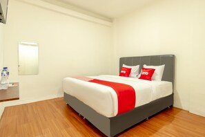 Quarto de hotel com cama, mesa de cabeceira e espelho na parede.