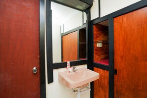 Casa de banho com porta de madeira, espelho e lavatório.