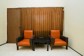 Um quarto com duas poltronas de couro laranja, uma pequena mesa preta e uma porta de madeira.