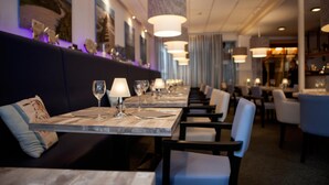Um restaurante com mesas compridas, cadeiras e uma fileira de cabines.
