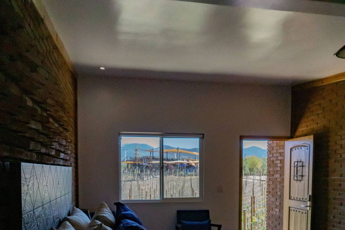Quarto com uma cama grande, vista para o exterior e uma parede de tijolos.
