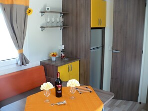 Uma cozinha compacta com uma mesa de jantar, uma garrafa de vinho e um abridor.