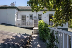 Um edifício branco com telhado verde, um deck de madeira e guarda-corpo branco.