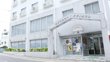 Um edifício branco com fachada em azulejos, grandes janelas e uma placa acima da entrada.