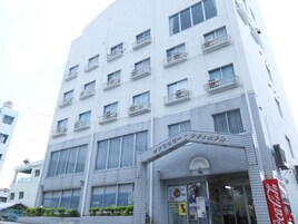 Um hotel com vários andares, fachada em azulejos, varandas e um letreiro da Coca-Cola.