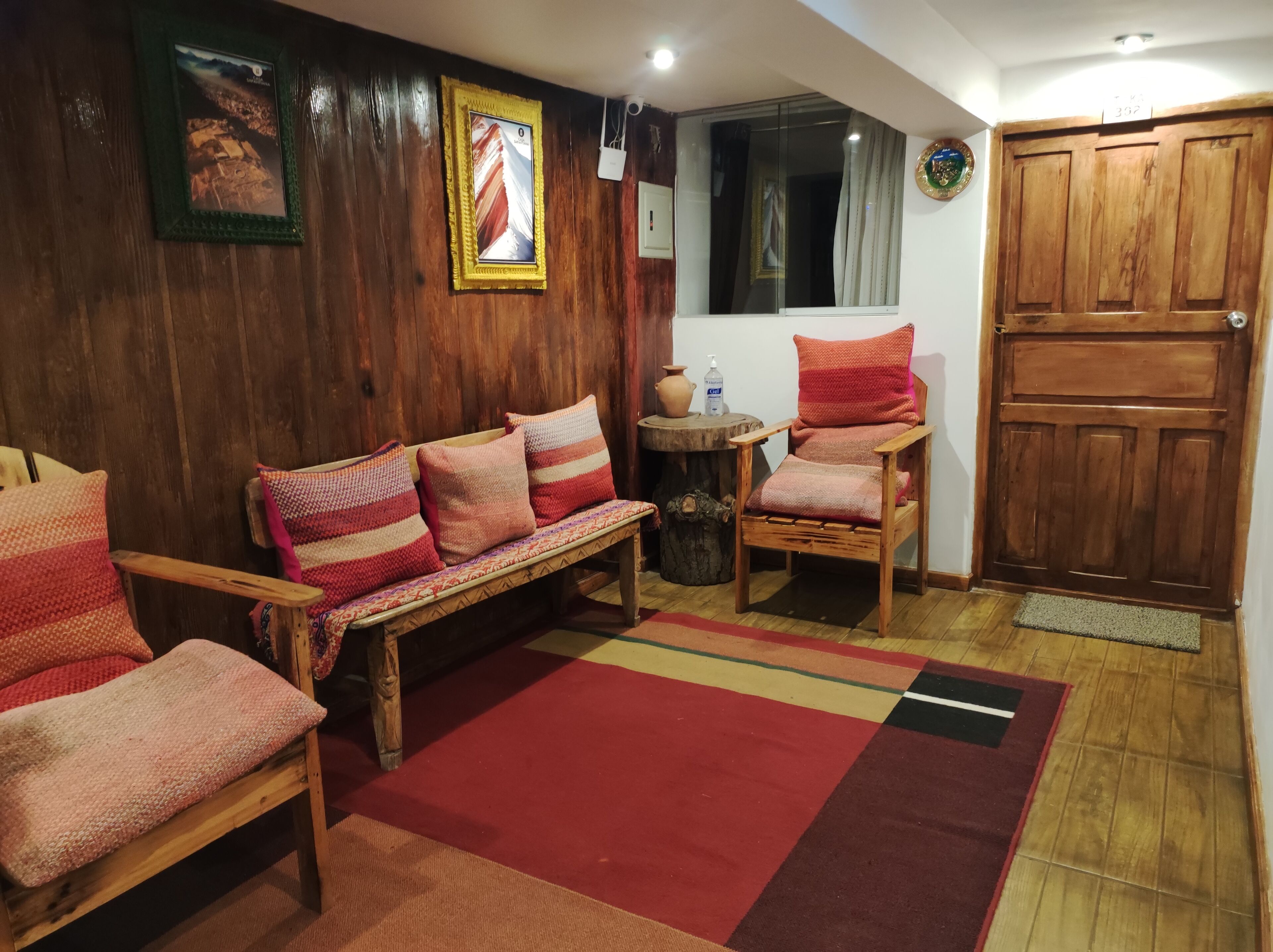 Um quarto aconchegante com um banco de madeira, duas cadeiras, uma mesa redonda pequena e uma porta de madeira.