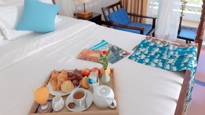 Cama bem arrumada com uma bandeja de itens para o café da manhã, incluindo croissants, frutas e um bule de chá.