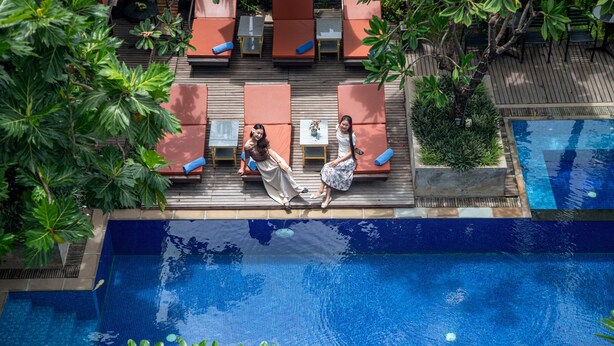 Vista aérea de uma área de piscina com espreguiçadeiras e uma mesa pequena.
