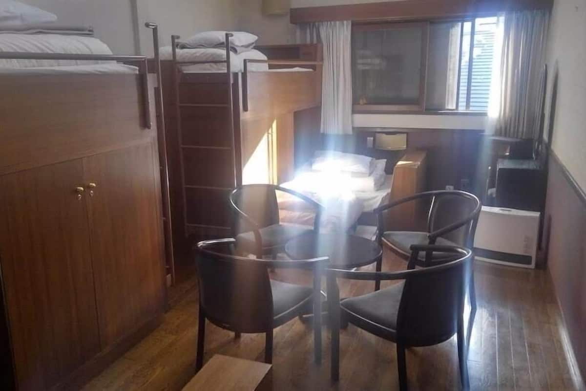 Quarto compacto com beliches, uma pequena escrivaninha e duas cadeiras.