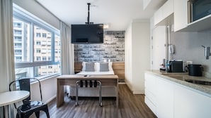 Quarto moderno com cama, mesa de cabeceira e televisão.