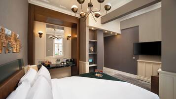 Quarto de hotel com uma cama grande, um candelabro, uma TV de tela plana, um espelho e uma mesa pequena com dois copos.