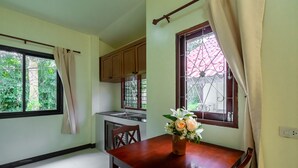 Cozinha com armários de madeira, uma mesa de jantar com cadeiras e uma janela com cortinas.