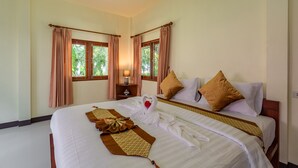 Quarto de hotel com duas camas, uma mesa de cabeceira com abajur e cortinas nas janelas.