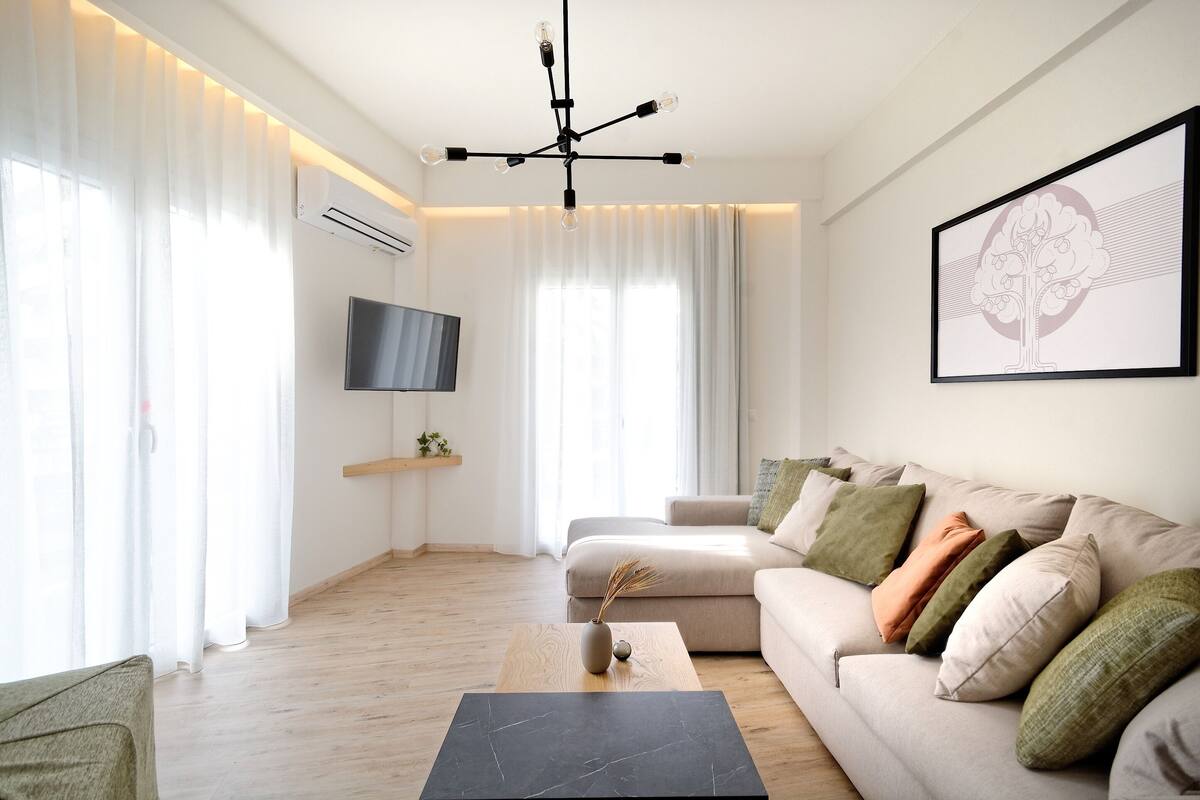 Uma sala de estar moderna com um sofá, uma mesa de centro e uma TV fixada na parede.