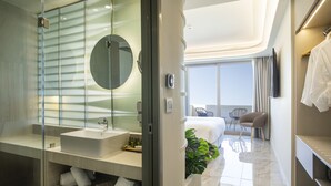Casa de banho moderna com chuveiro de vidro, um espelho grande e uma pia com produtos de higiene pessoal.