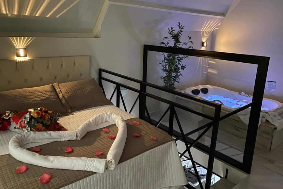 Quarto com cama, divisória de vidro, vista para uma área de spa e varanda.