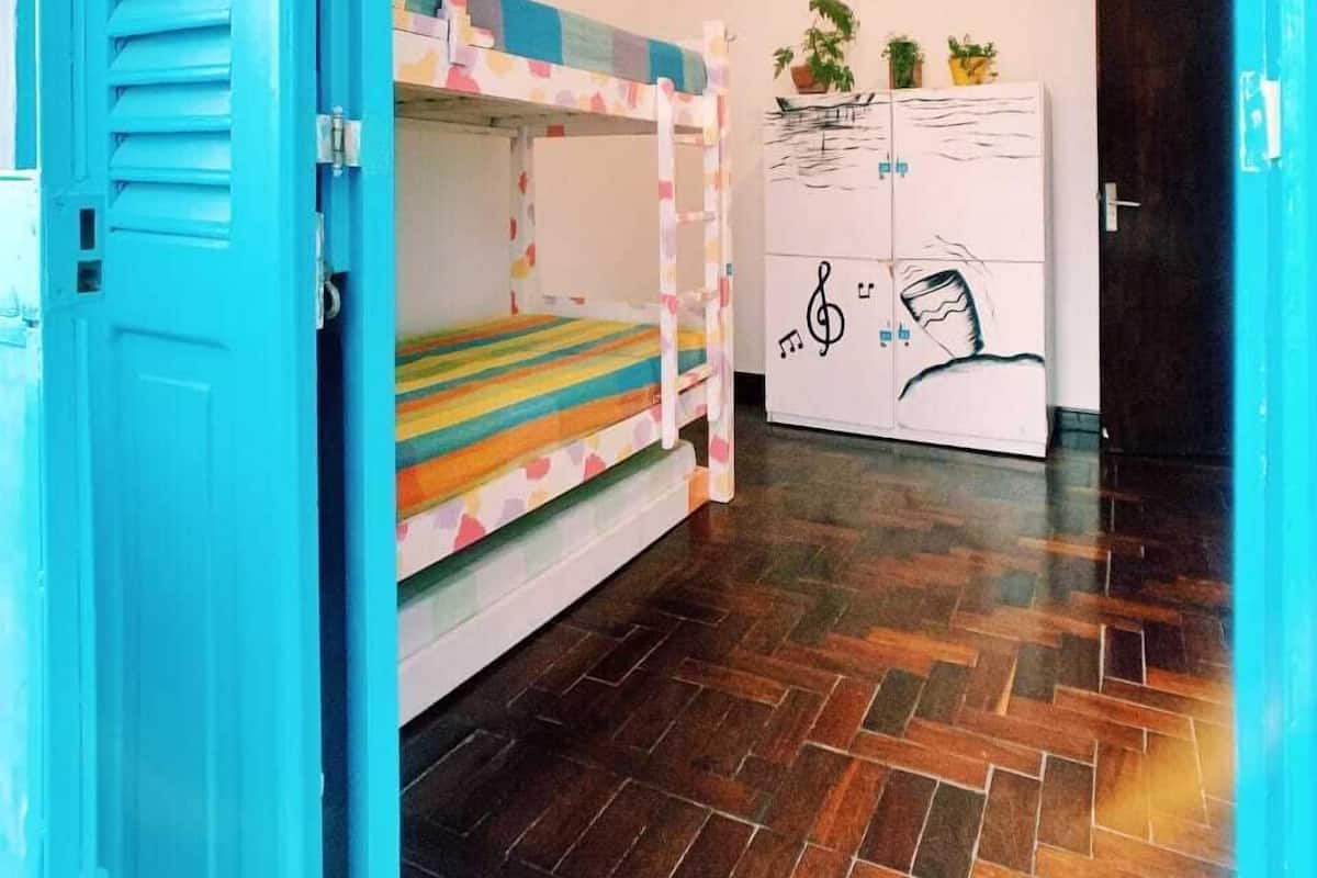 Quarto com beliche, um armário branco com notas musicais e um ventilador de teto.
