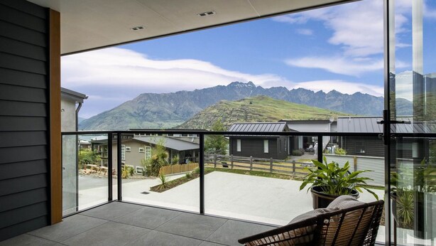 Uma varanda com vista para montanhas, uma cadeira e um vaso com planta.