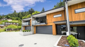 Uma casa moderna de dois andares com garagem, varanda e um jardim bem cuidado.