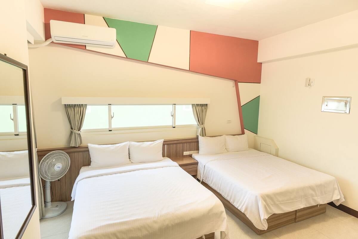 Quarto de hotel com duas camas, um ventilador e um ar condicionado.