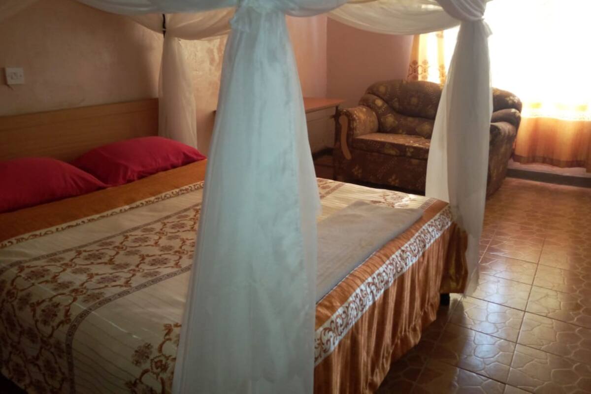 Quarto com cama, uma cadeira e dossel.