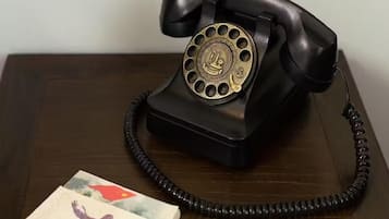 Um telefone antigo preto com mostrador rotativo sobre uma mesa de madeira.