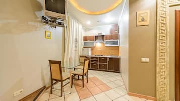Cozinha compacta com área de refeições, TV fixada na parede e moldura de porta decorativa.
