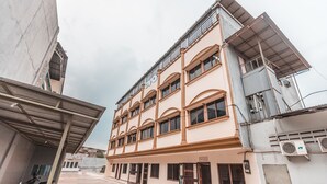 Um edifício de vários andares com fachada plana, janelas amplas e entrada coberta.