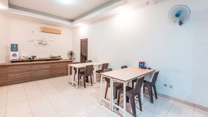 Um quarto espaçoso com um longo balcão de madeira, várias mesas e cadeiras.