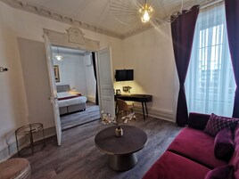 Quarto de hotel moderno com uma cama, uma escrivaninha com um computador, uma mesa de centro redonda e um sofá.