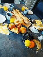 Uma mesa de café da manhã com croissants, pão, frutas e suco.