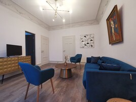 Uma sala de estar moderna com um sofá azul, uma mesa de centro e uma TV em um armário de madeira.