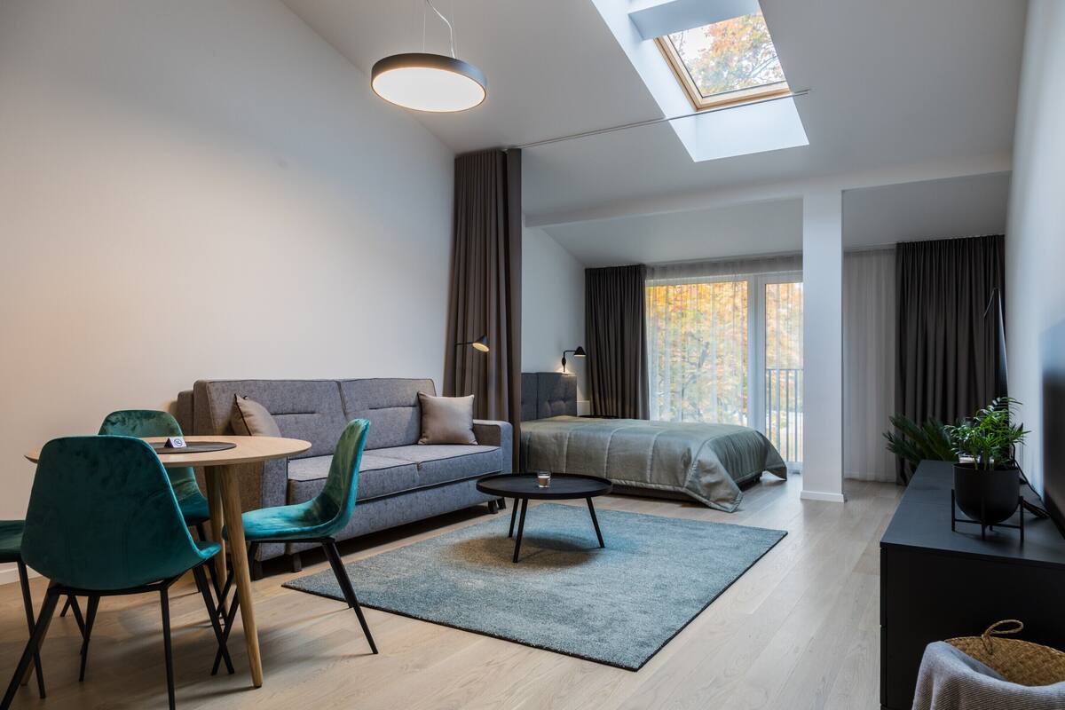 Uma sala de estar moderna com um sofá, cadeiras, uma mesa de centro e um claraboia.