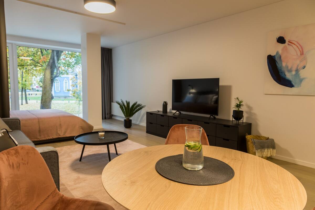Uma sala de estar moderna com um sofá, uma mesa de centro, uma televisão e uma mesa de jantar.
