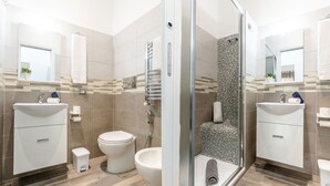 Um banheiro moderno com duas pias, vaso sanitário, bidê e área de chuveiro.