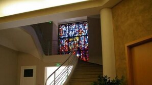 Escadaria levando a uma janela de vitrais.