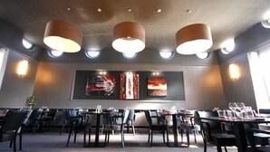 Uma sala de conferências com mesas, cadeiras, iluminação no teto e obras de arte na parede.