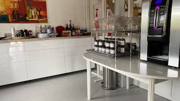 Uma cozinha moderna com cafeteira, potes de condimentos e um quadro na parede.