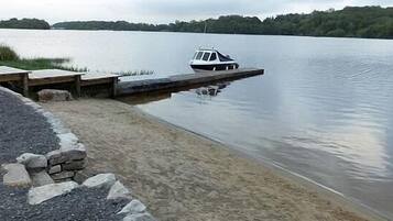 Um barco atracado em um lago tranquilo, com um cais de madeira e um muro de pedra.