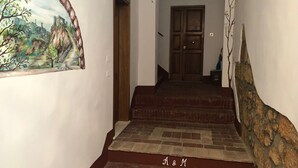 Uma escadaria leva a uma porta de madeira, com uma parede de pedra de um lado e um mural do outro.