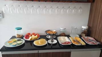 Uma bancada de cozinha com diversos alimentos e um espaço para vinhos acima.