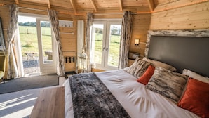 Quarto de cabana de madeira com cama, cortinas e vista para o exterior.