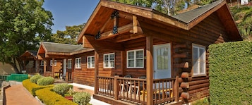 Uma fileira de cabanas de tronco com varandas de madeira e um jardim bem cuidado.