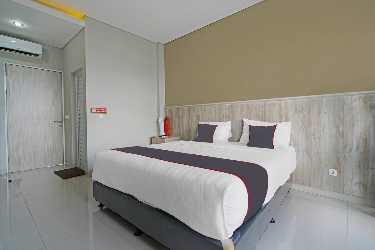 Quarto de hotel com uma cama grande, uma mesa de cabeceira e uma porta.