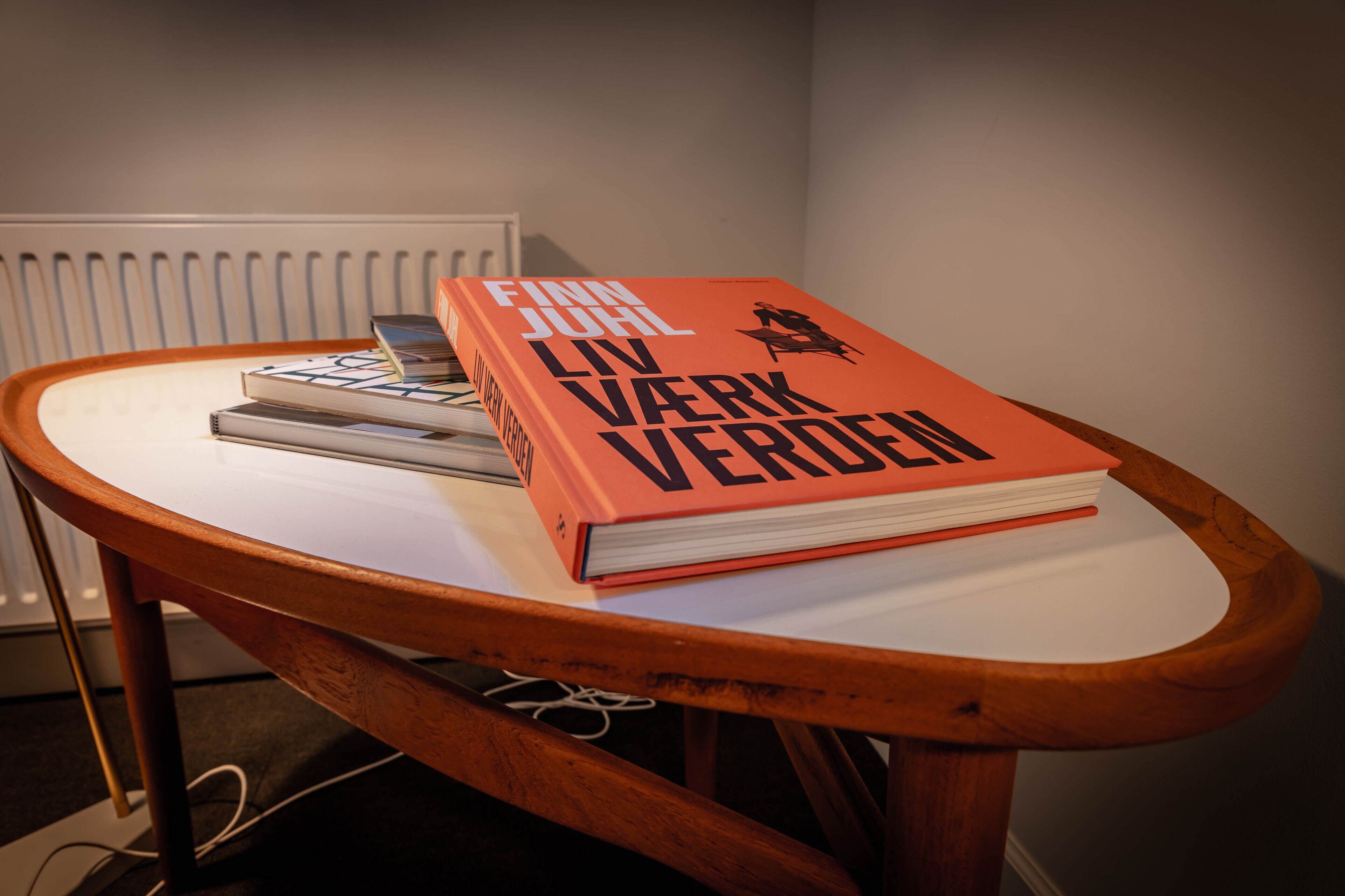 Um livro intitulado 'Finn Juhl Liv Værk Verden' sobre uma mesa de madeira.