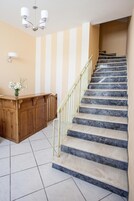 Uma escadaria com degraus de mármore e uma mesa de recepção de madeira com um vaso de flores.