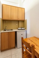 Cozinha compacta com armários de madeira, pia, pequena geladeira e mesa de jantar de madeira com cadeiras.