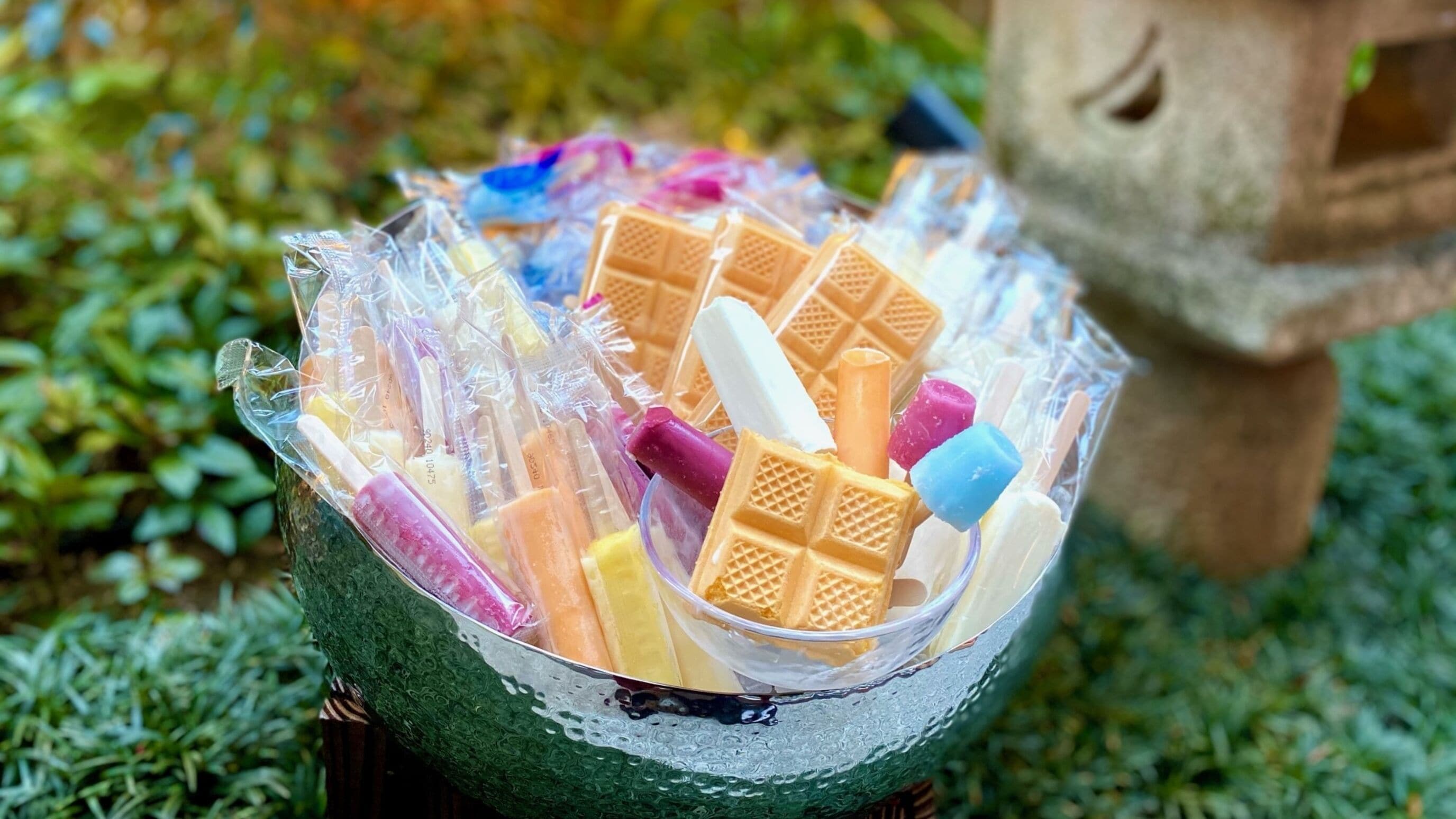 Um recipiente de plástico transparente cheio de diversos sorvetes e cones de waffle.