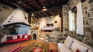 Um quarto aconchegante com parede de pedra, teto de madeira, cama e sofá vermelho.